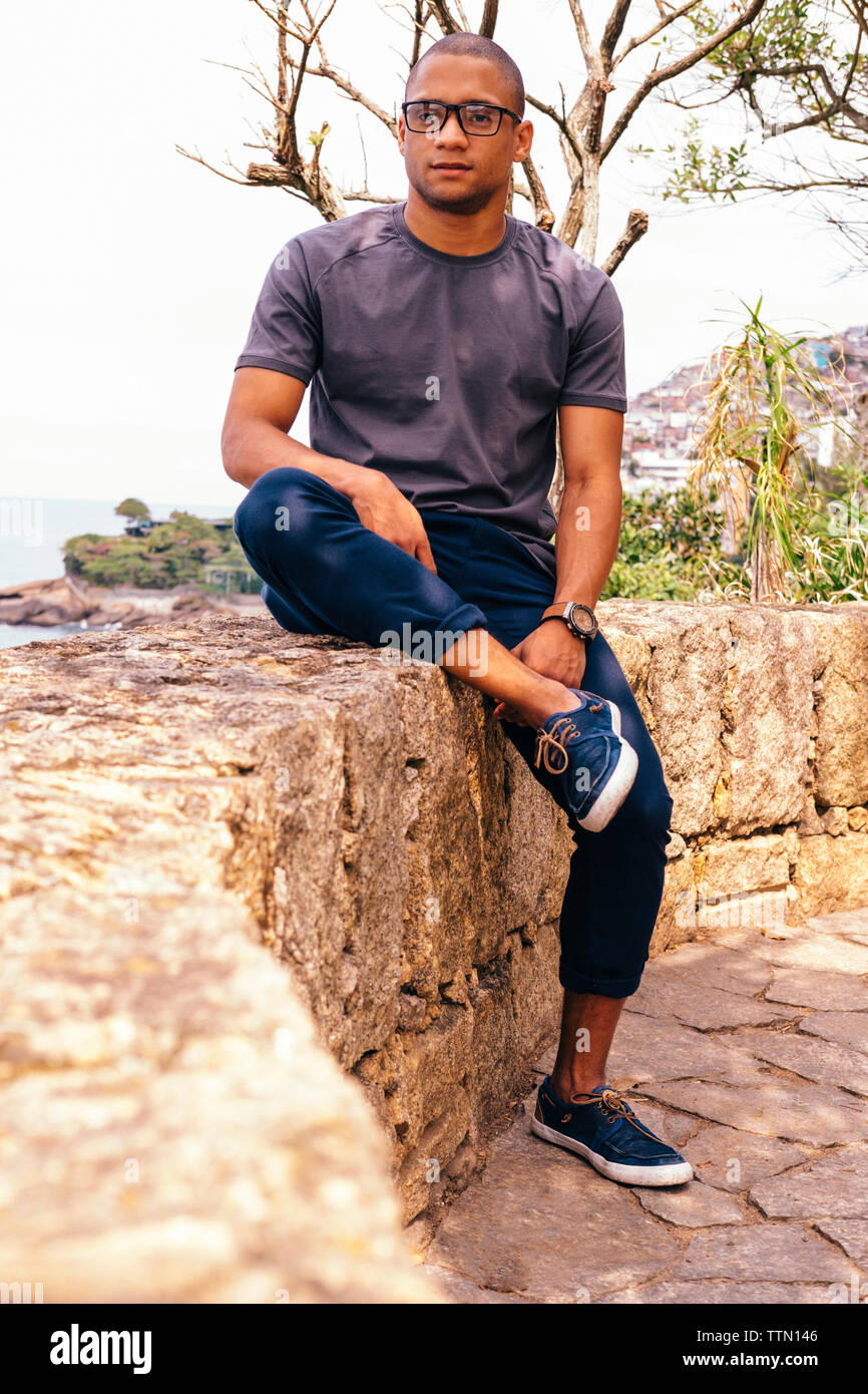 Young man sitting on wall hi-res stock photography and images - Alamy