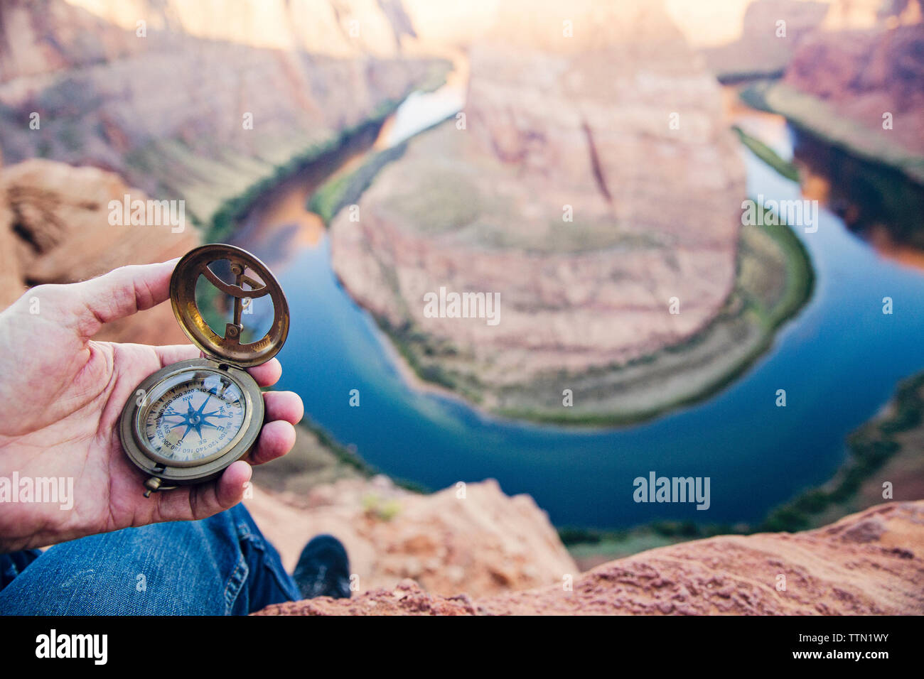 Low section of man holding navigational compass against Horseshoe Bend ...