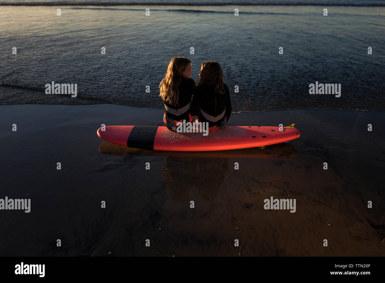 sisters talking while sitting on their surfboard on the beach Stock ...