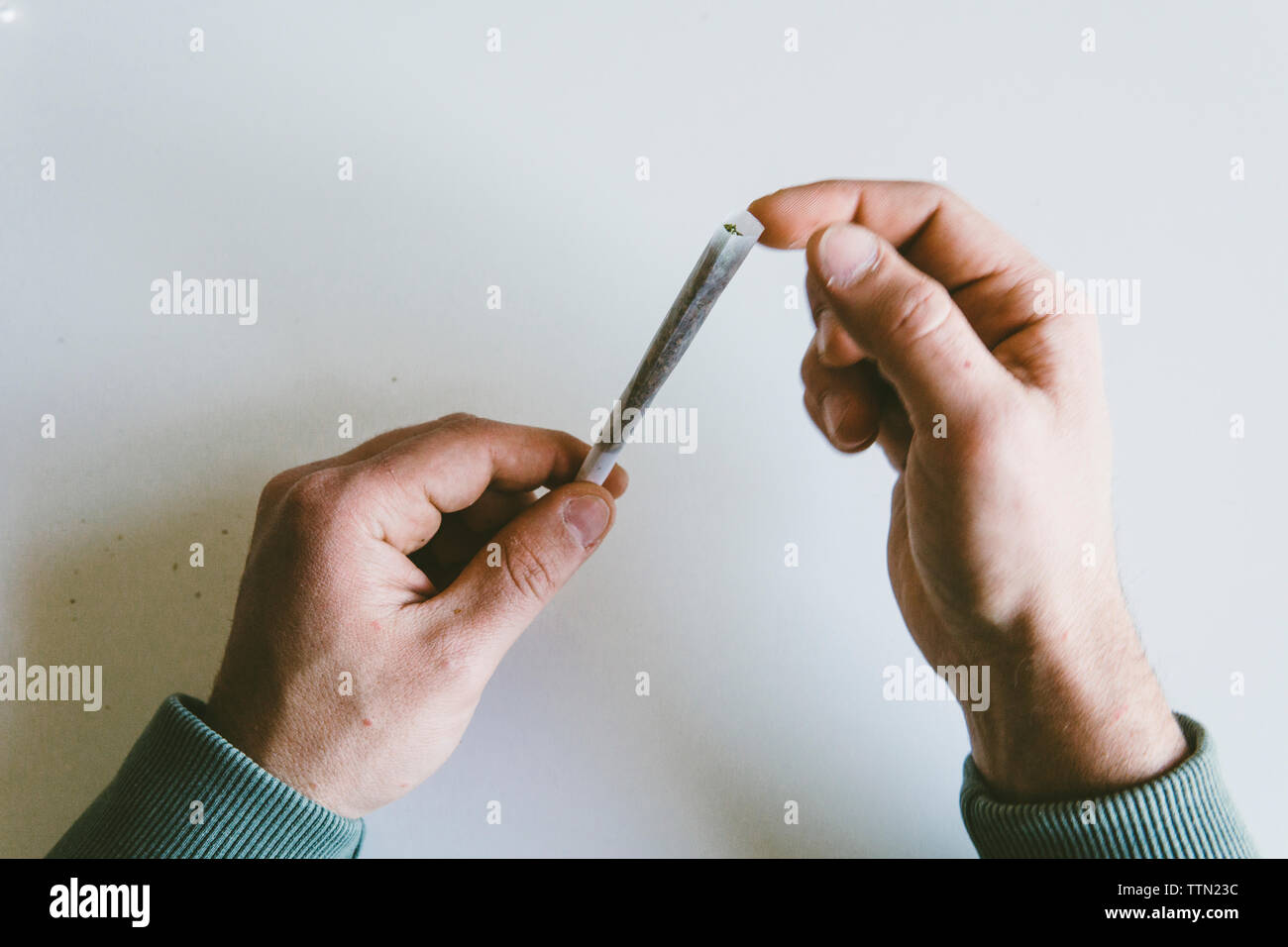 Cropped hands of man making marijuana joints over white table Stock ...