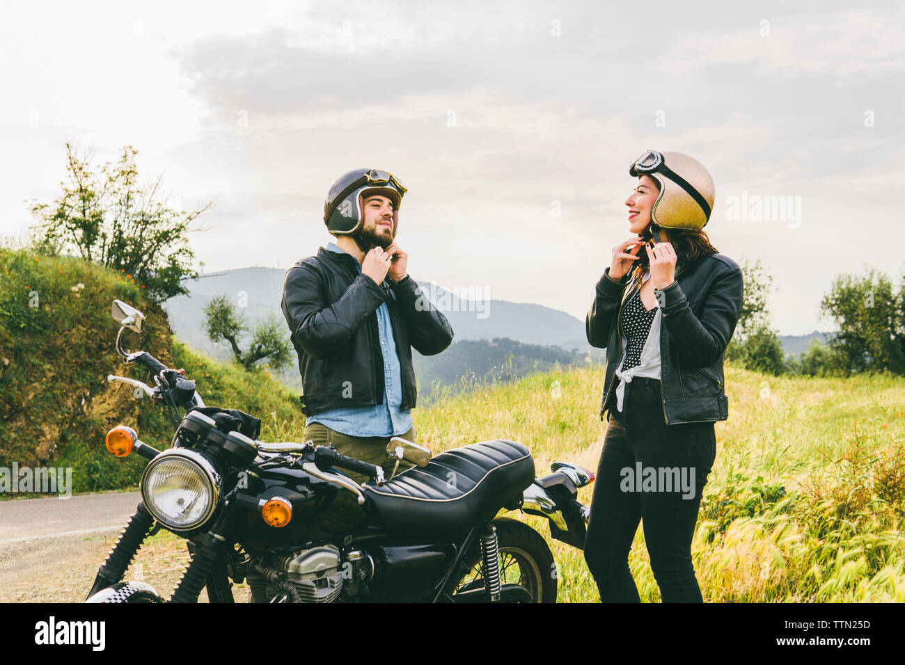 Couple wearing helmets while standing by motorcycle against sky Stock ...