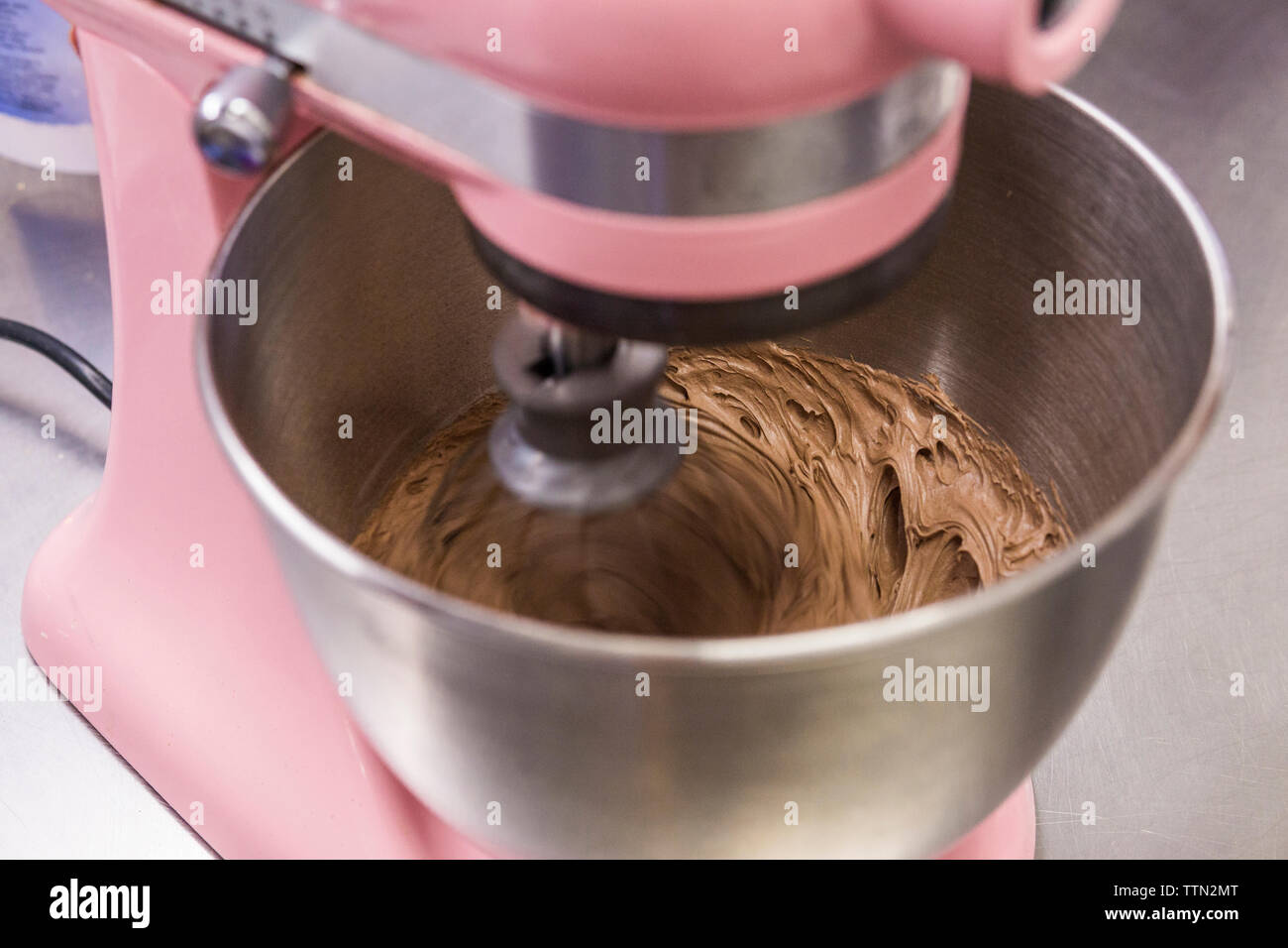 High angle close-up of chocolate batter mixing in mixer on kitchen ...