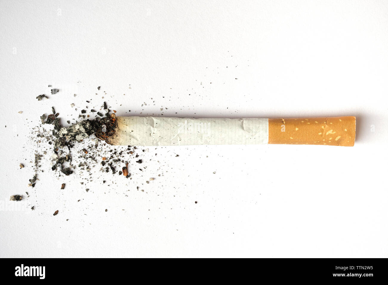 Frontal close up of a single half burned cigarette with ashes isolated ...