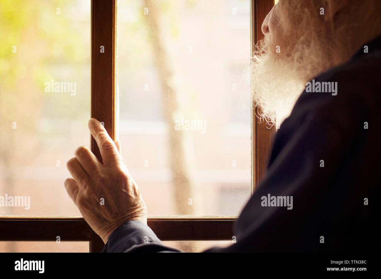 Senior man looking through window Stock Photo - Alamy