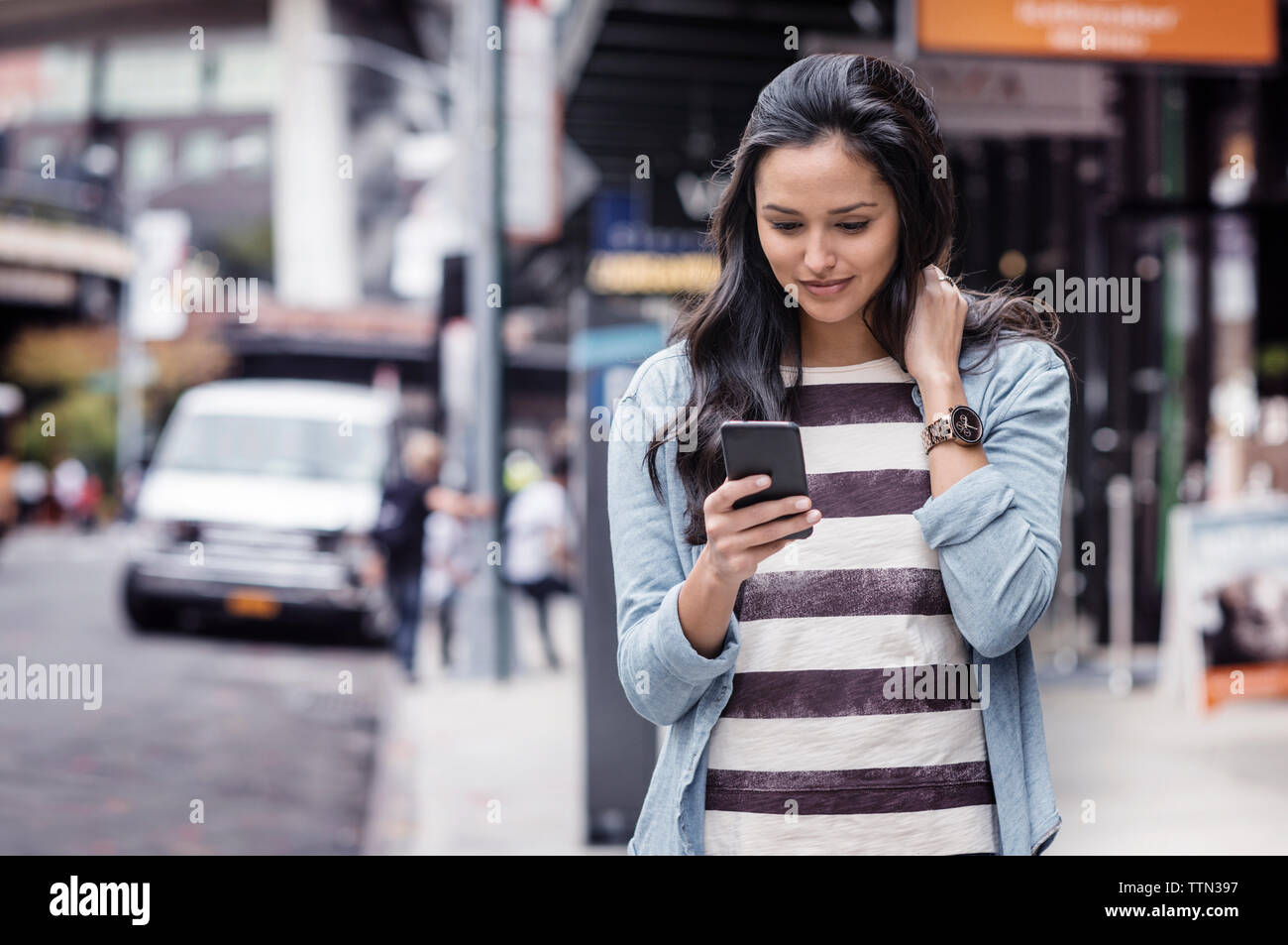 Young woman texting on sidewalk Stock Photo - Alamy