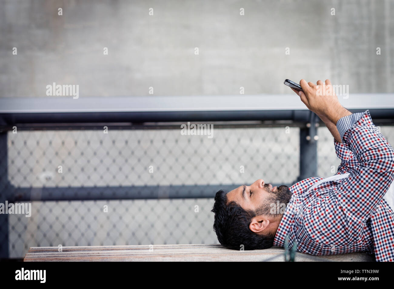 Side-view of man texting on bench Stock Photo - Alamy