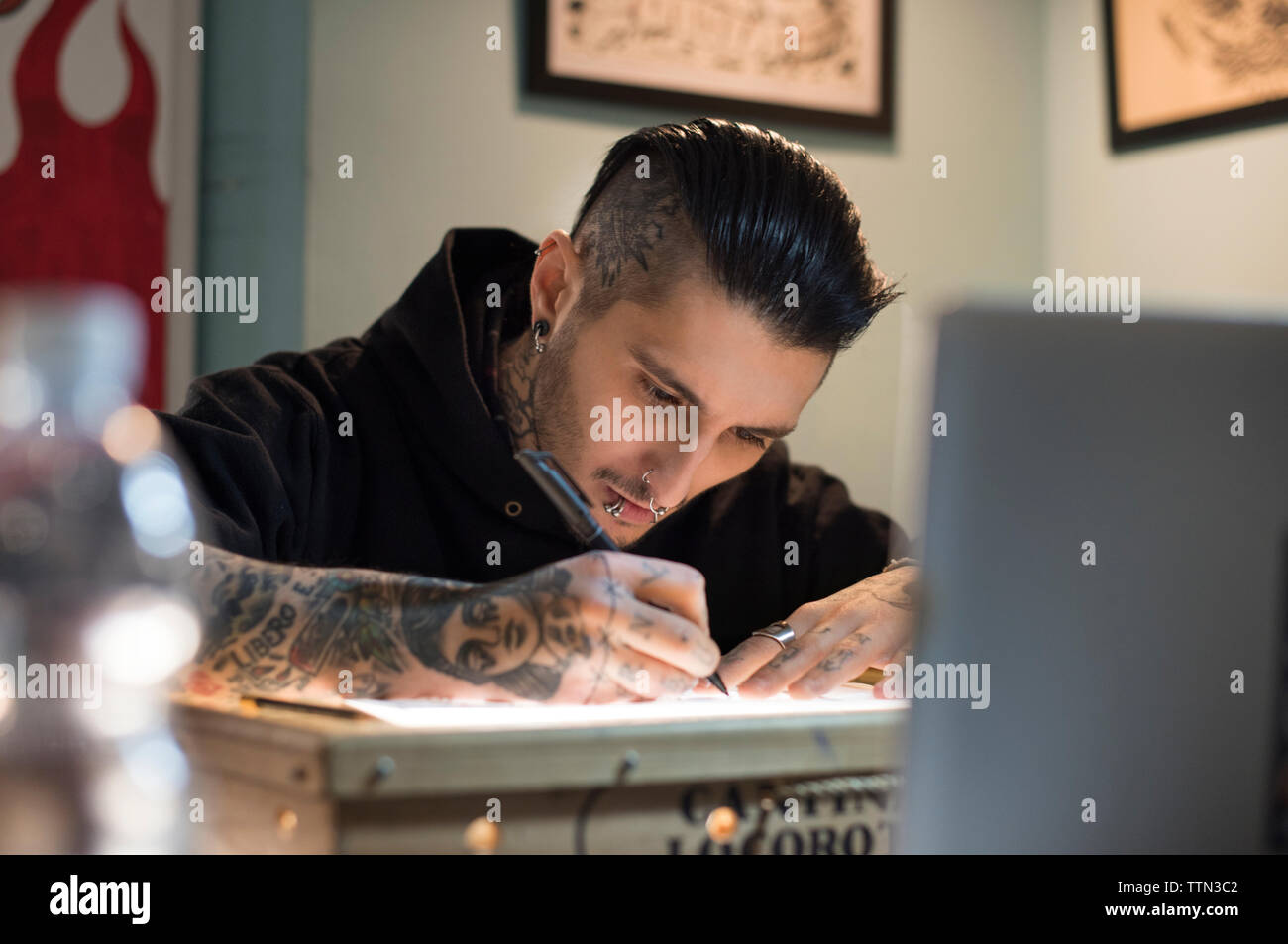 Male tattoo artist drawing design on paper at studio Stock Photo - Alamy