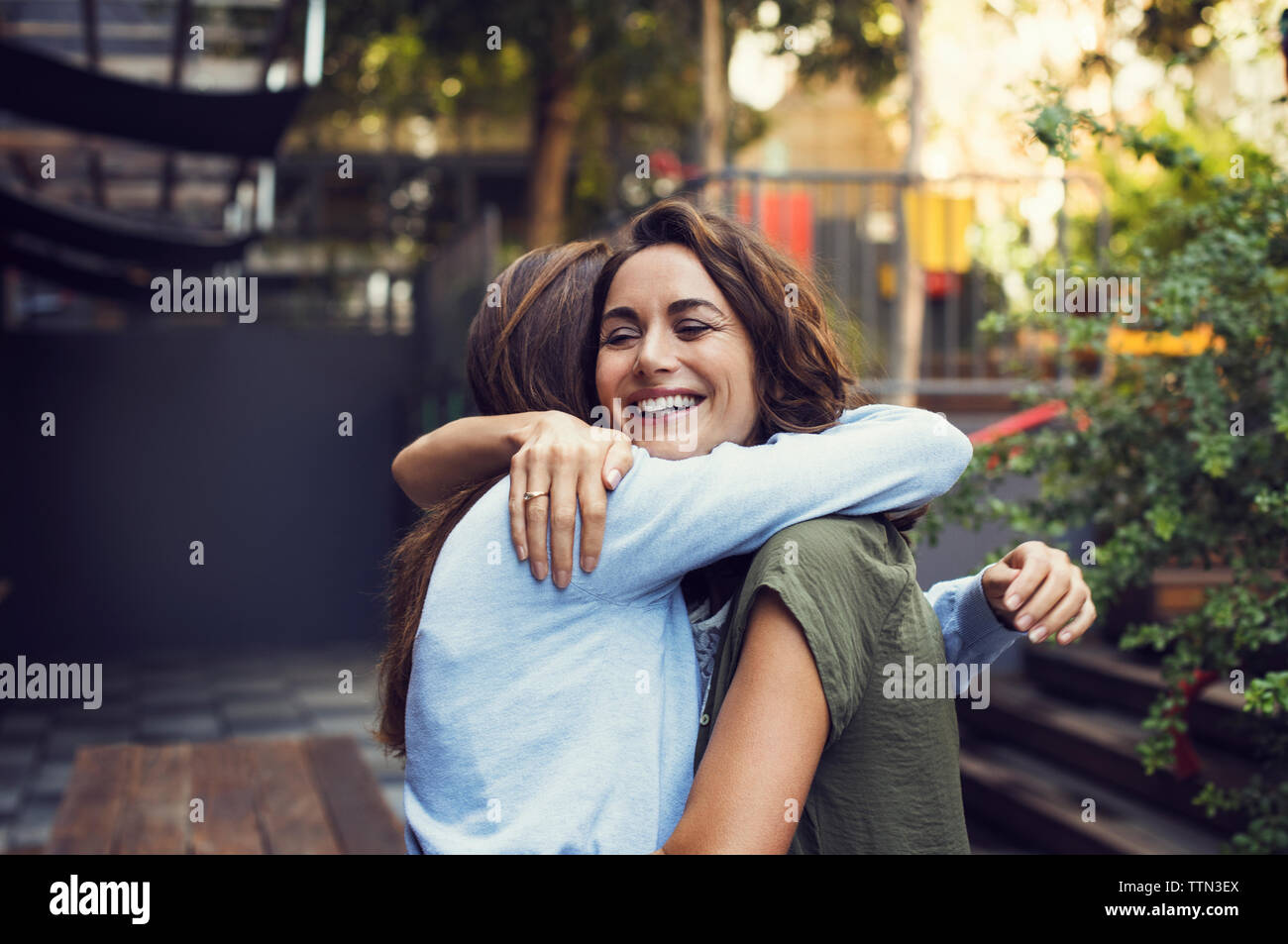 Affectionate mature women embracing at sidewalk cafe Stock Photo - Alamy