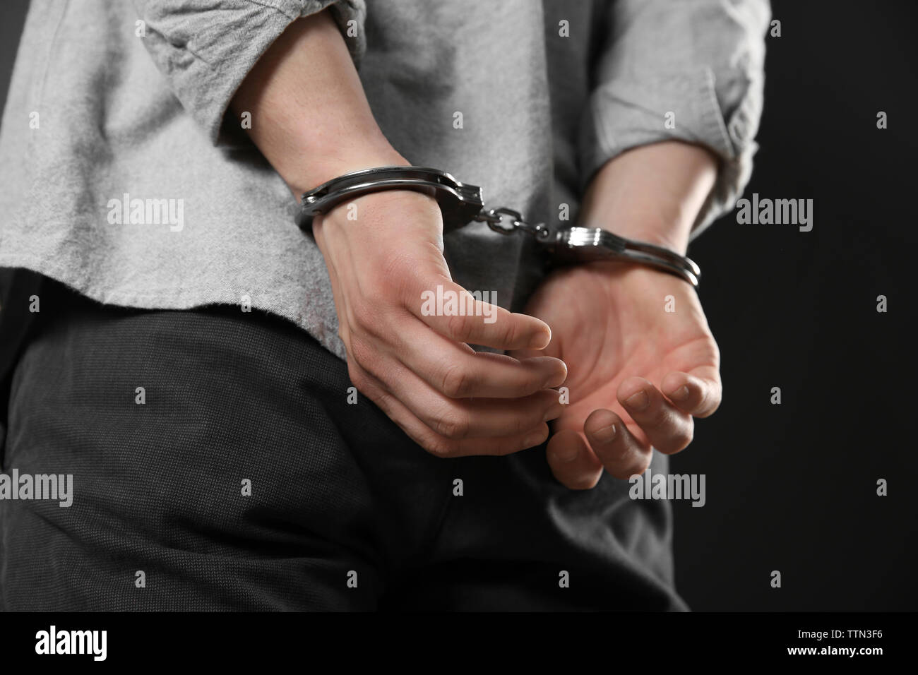 Man in handcuffs on grey background Stock Photo - Alamy