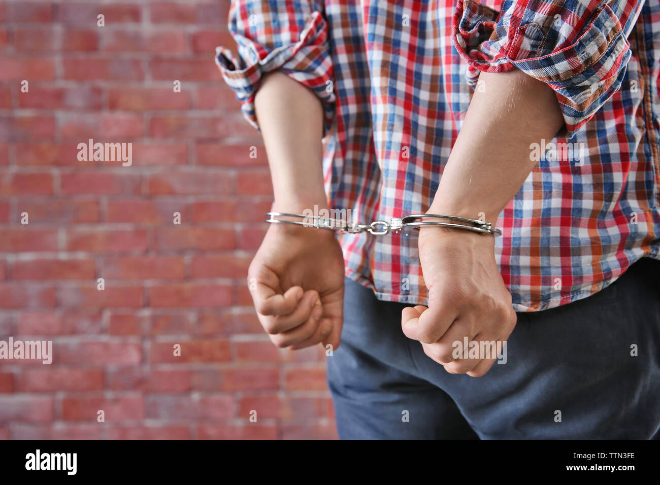 Man in handcuffs on brick wall background Stock Photo - Alamy
