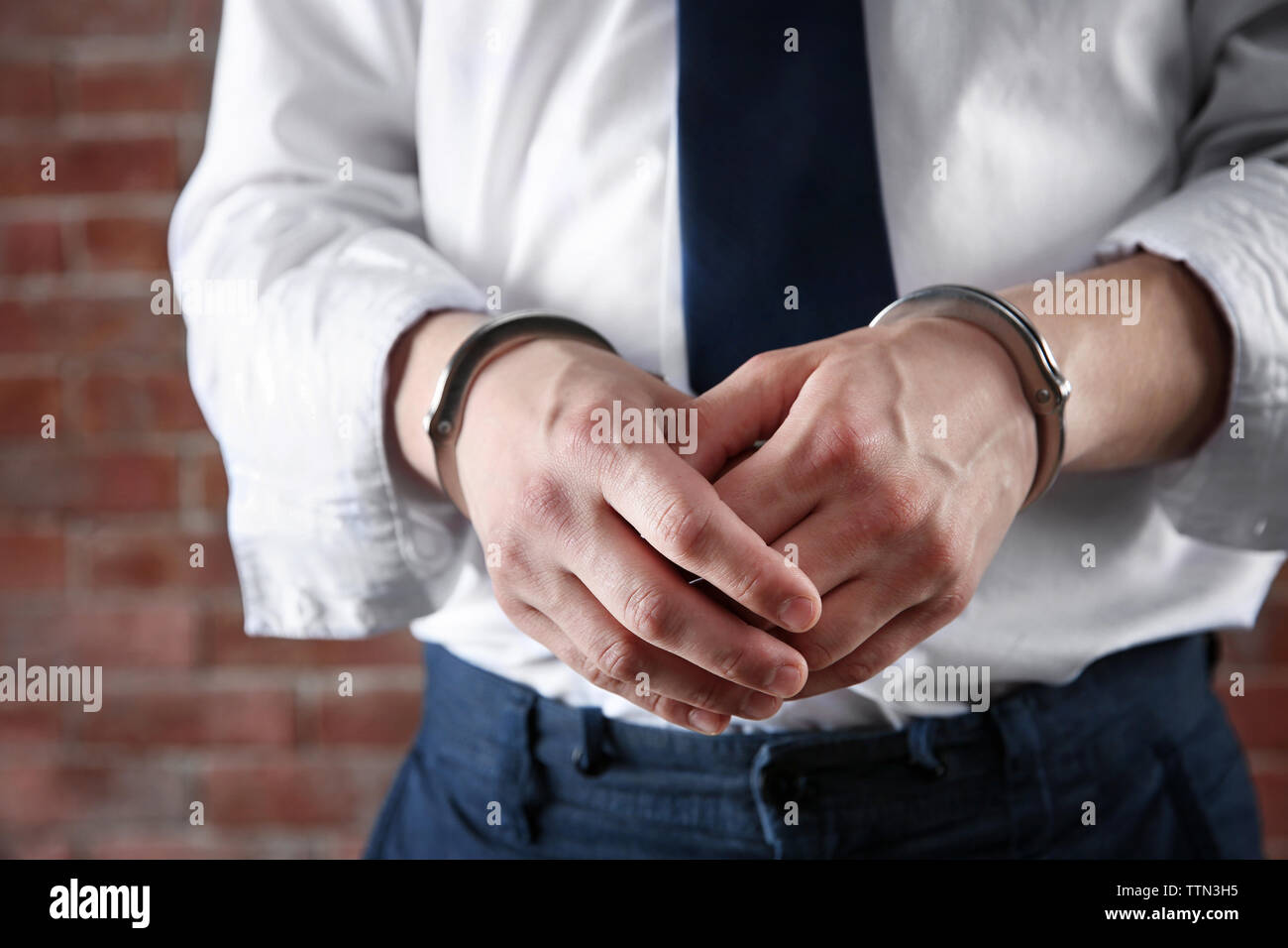 Man in handcuffs on brick wall background Stock Photo - Alamy