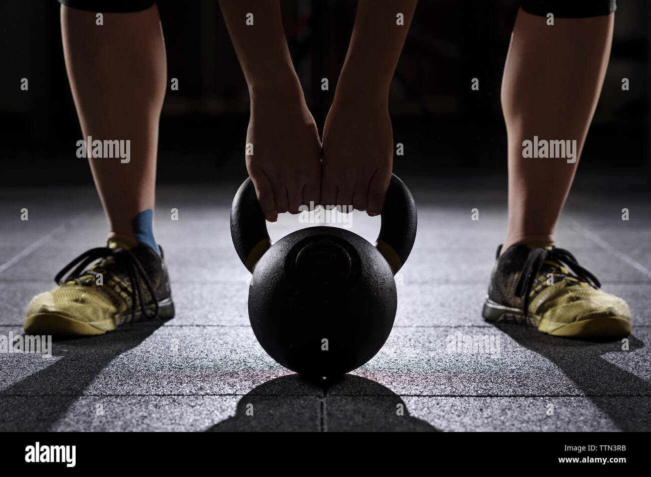 Low section of athlete lifting kettle bell at gym Stock Photo - Alamy