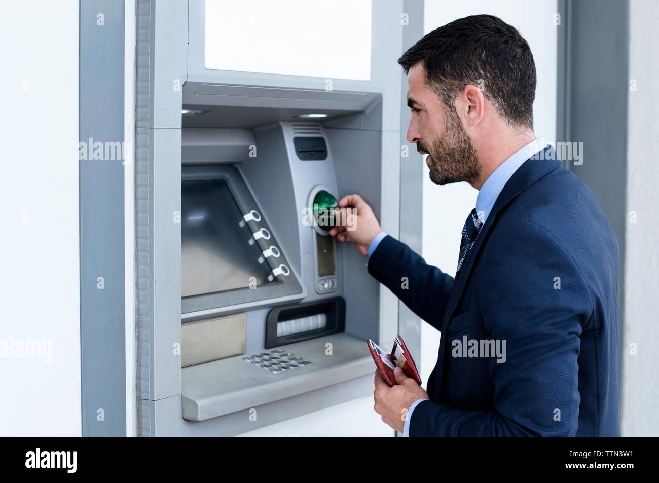 Side view of businessman using ATM at subway station Stock Photo - Alamy