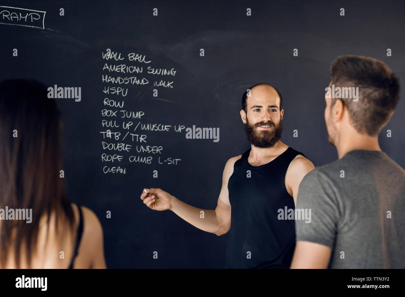 Fitness instructor explaining to athletes in gym Stock Photo - Alamy