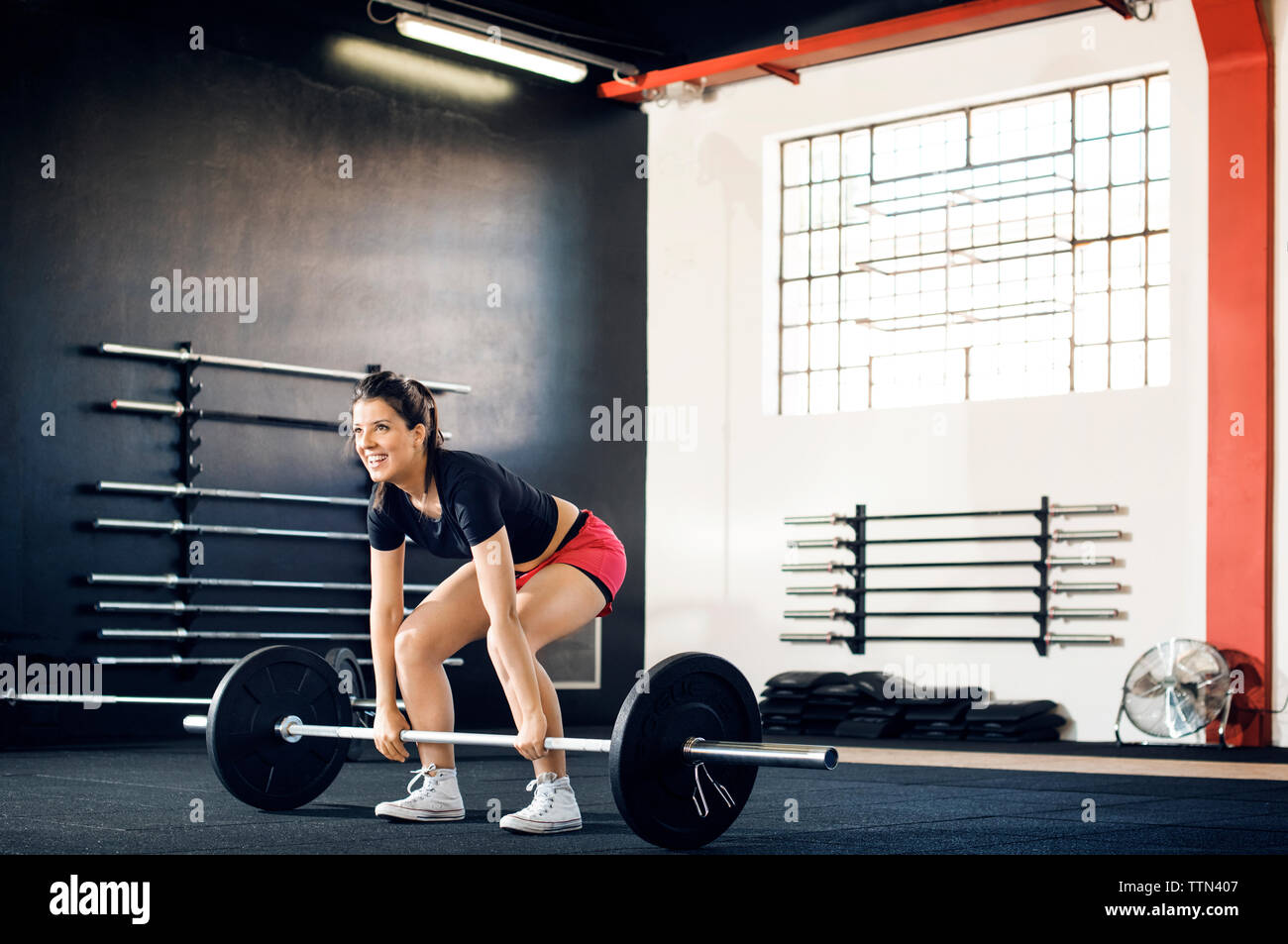 Happy woman lifting barbell in gym Stock Photo - Alamy