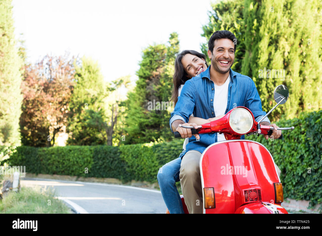 Happy couple enjoying motor scooter ride at park Stock Photo - Alamy