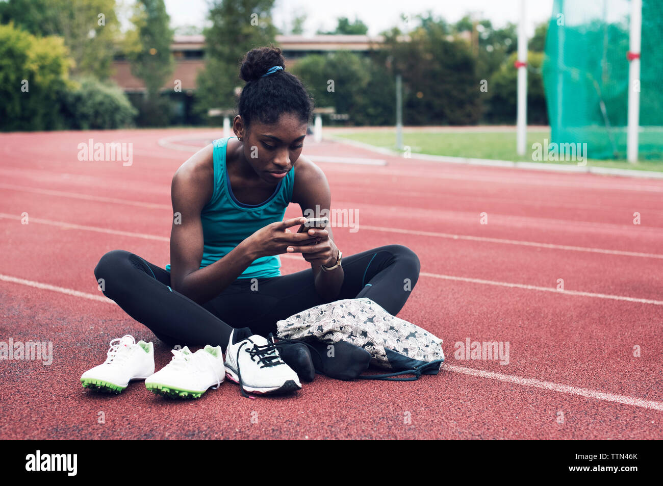 Athlete using mobile phone while sitting on track Stock Photo - Alamy