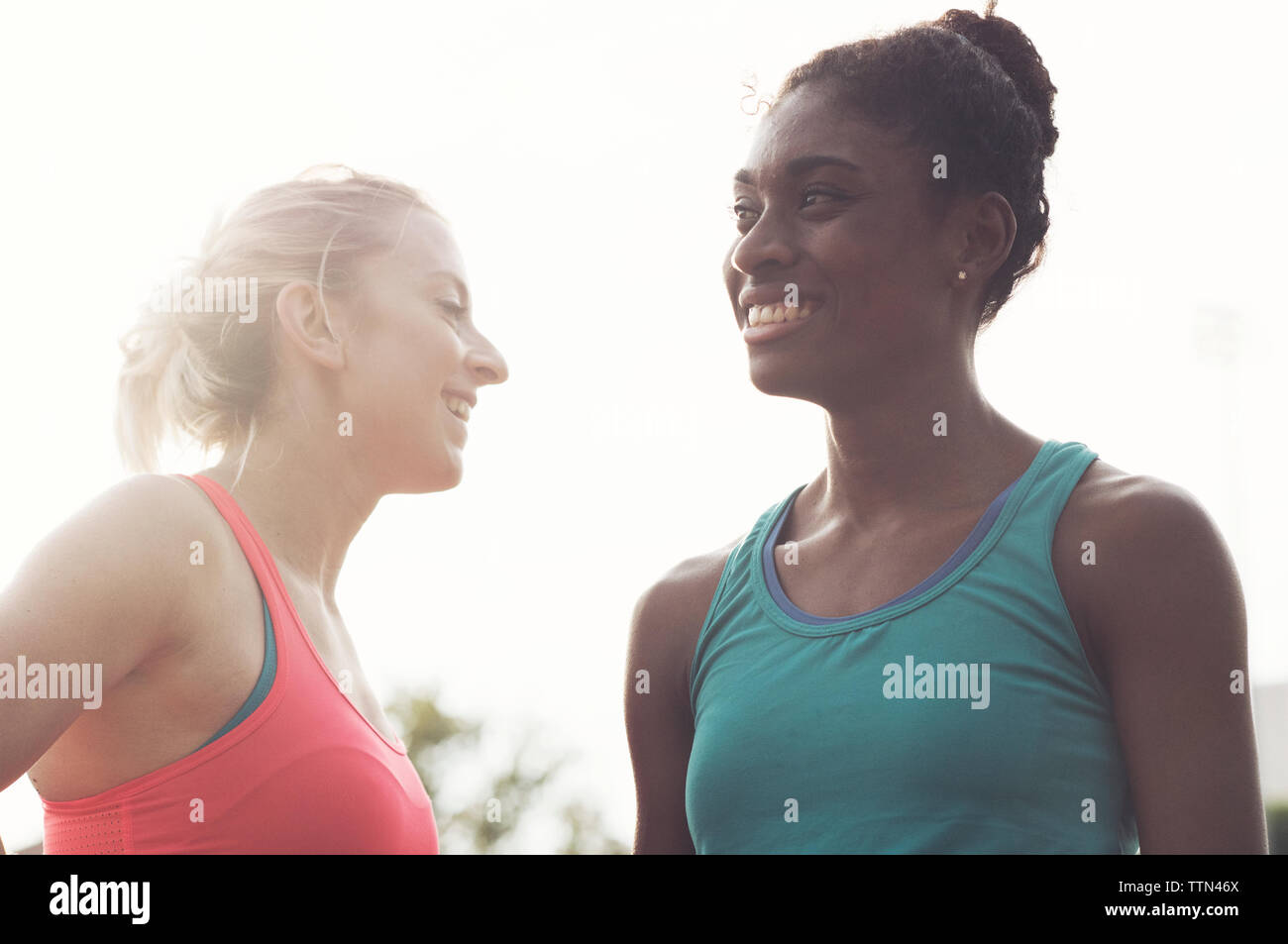 Low angle view of female athletes talking while standing against sky ...