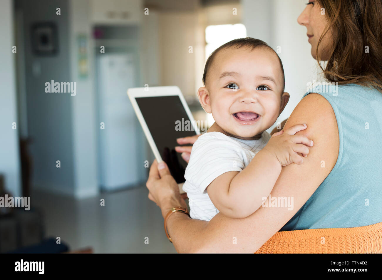 Mother carrying baby boy in carrier while using tablet computer Stock ...