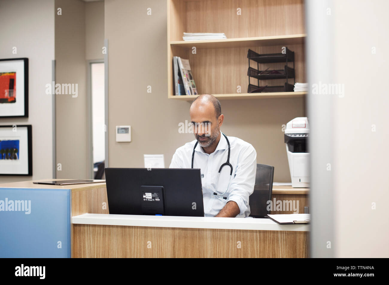 Doctor using desktop computer while working in room at hospital seen ...