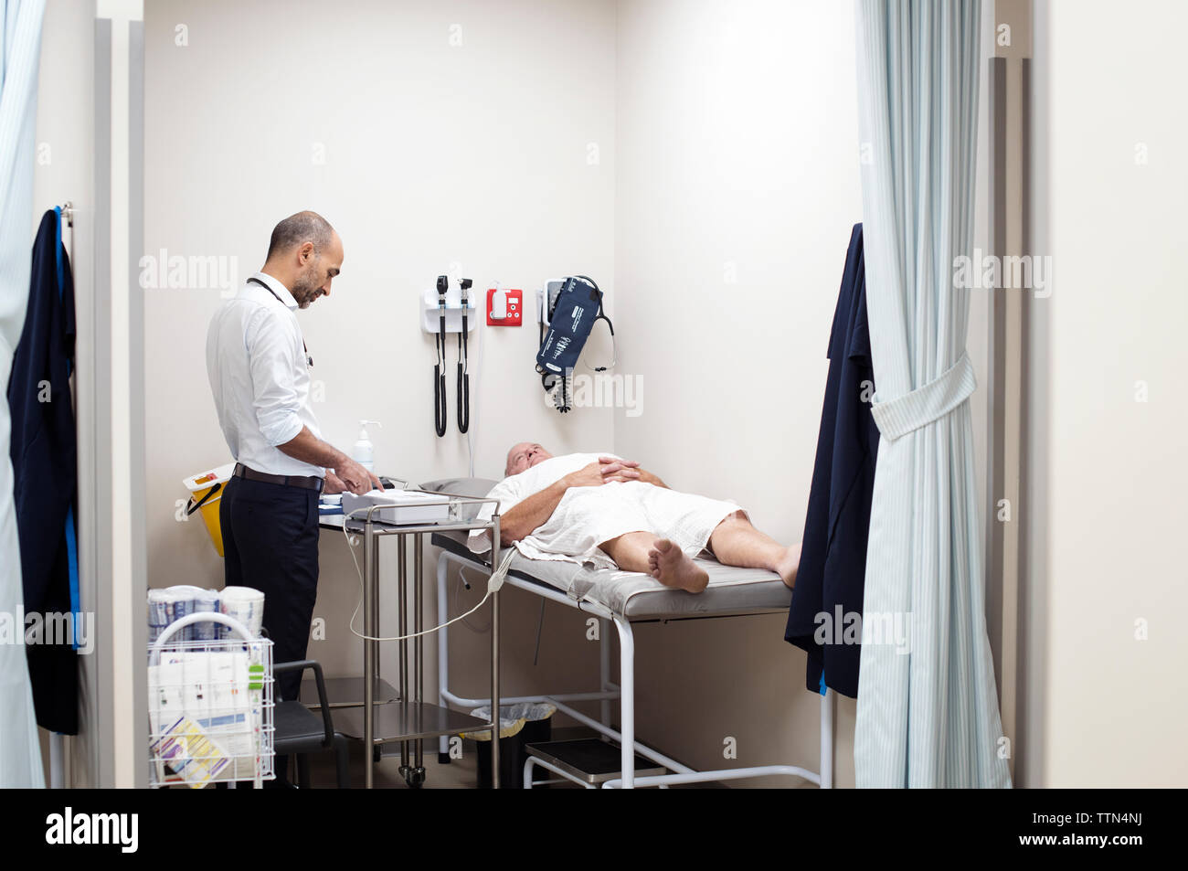 Doctor examining patient seen through door Stock Photo - Alamy