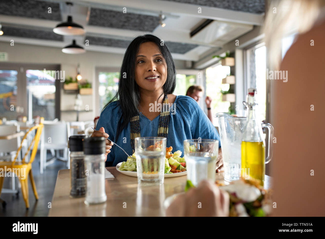 Female friends talking while eating food on table in cafeteria Stock ...