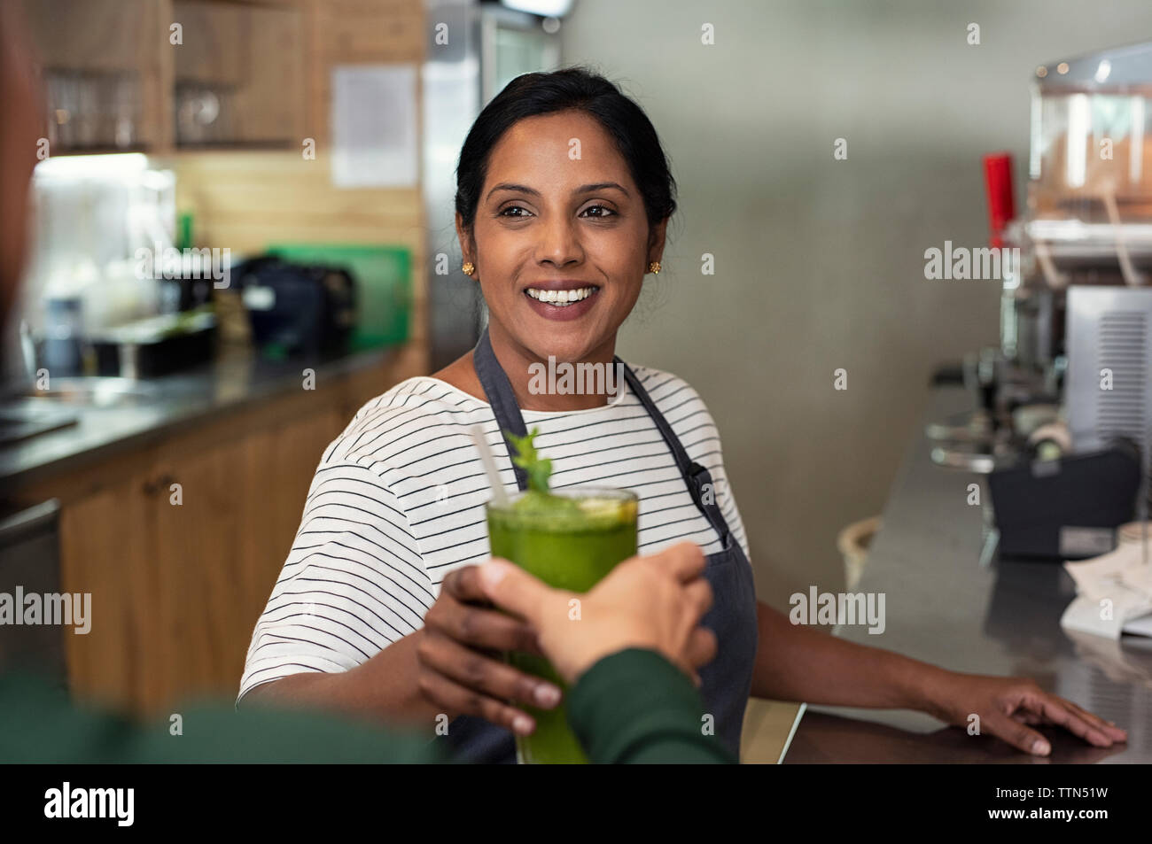Female owner giving drink to customer in cafeteria Stock Photo - Alamy