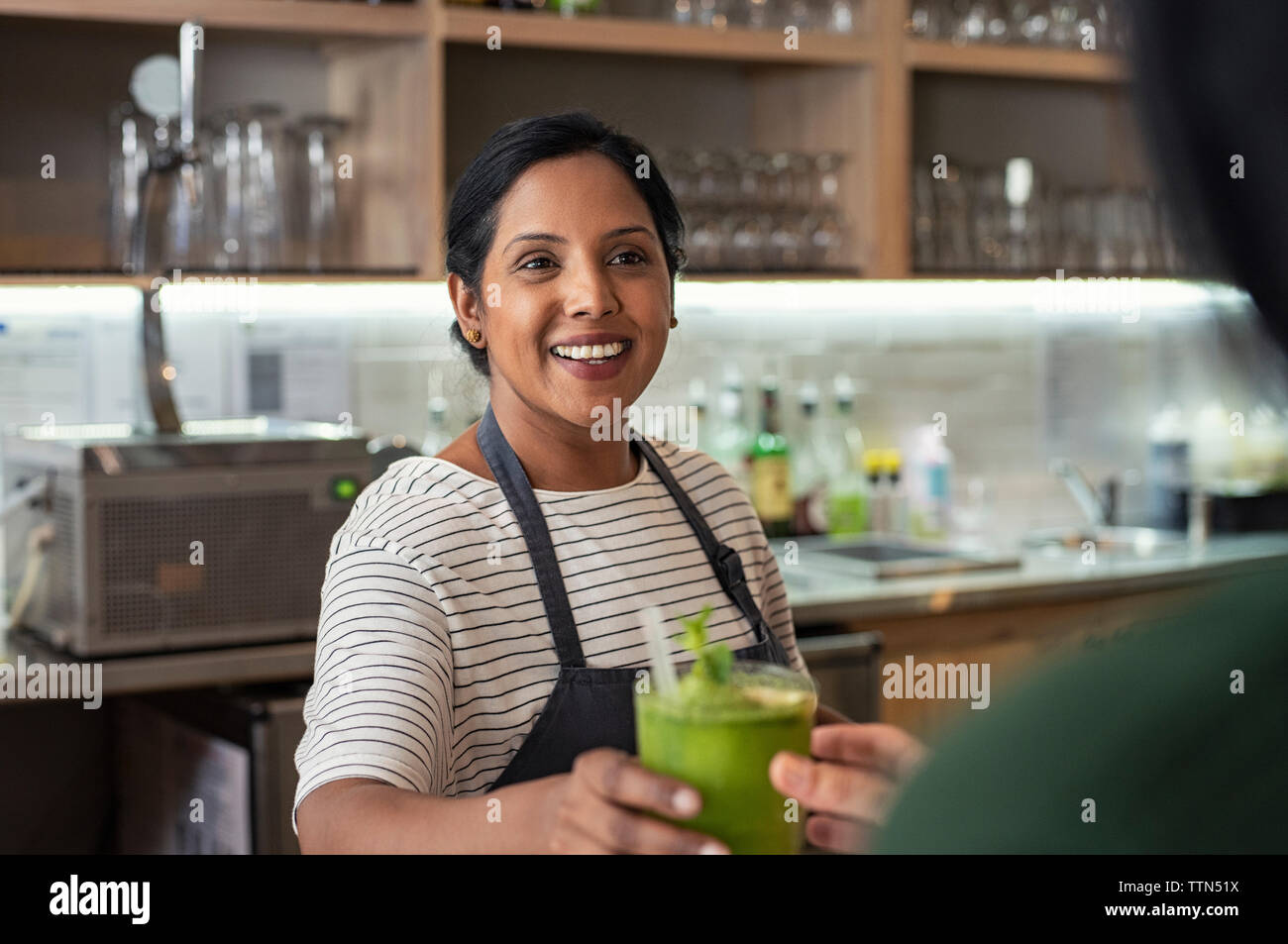 Owner giving drink to female customer in cafeteria Stock Photo - Alamy