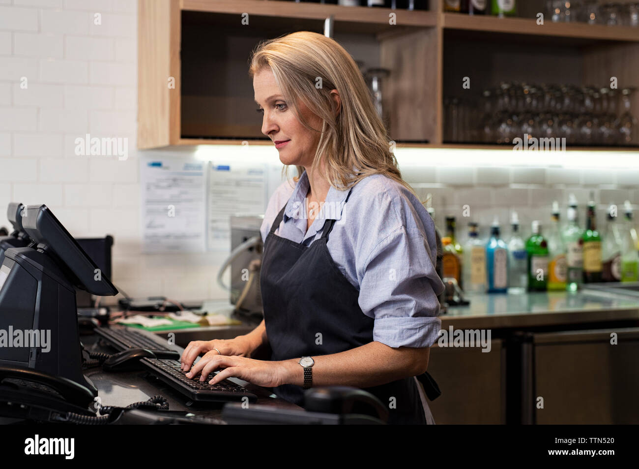 Female owner using computer while standing in cafeteria Stock Photo - Alamy