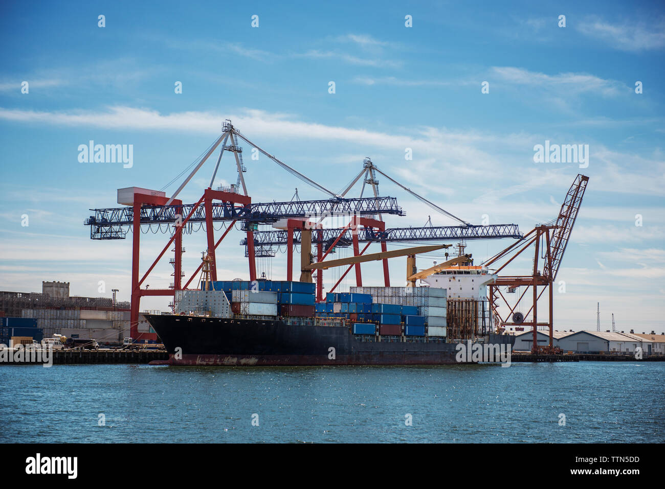 Container ship moored at commercial dock against sky Stock Photo - Alamy