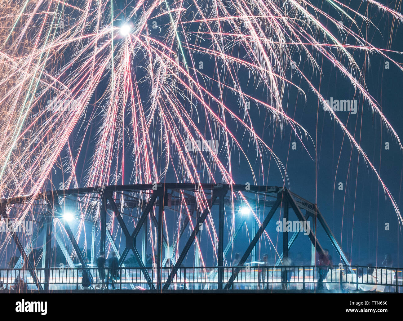 Low angle view of firework display over bridge in sky Stock Photo - Alamy