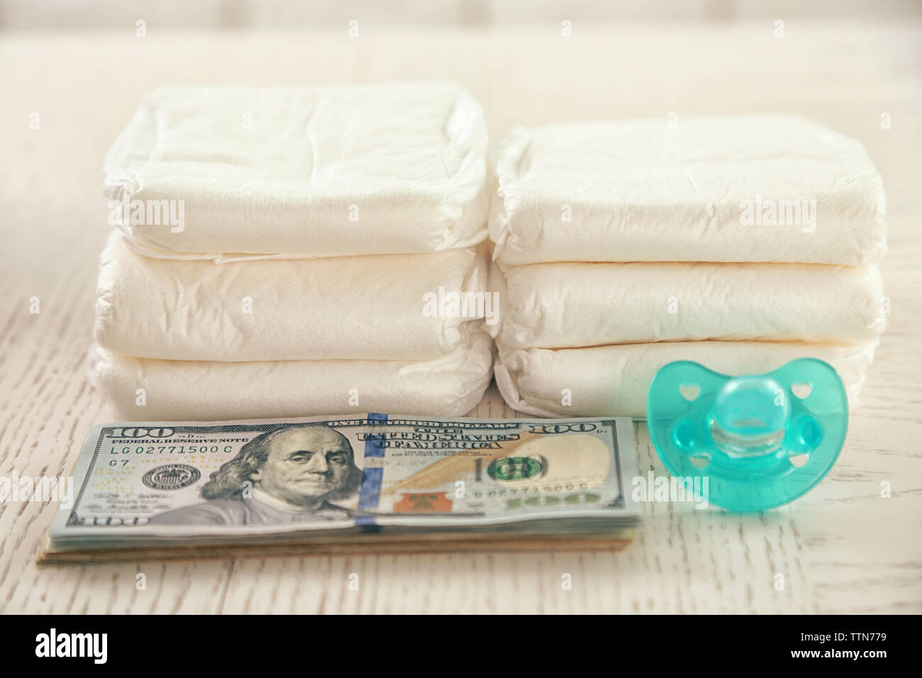 Parenting expenses concept. Pile of diapers, pacifier and money Stock ...