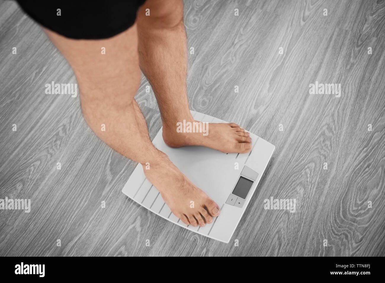 Man standing on weight scale Stock Photo - Alamy