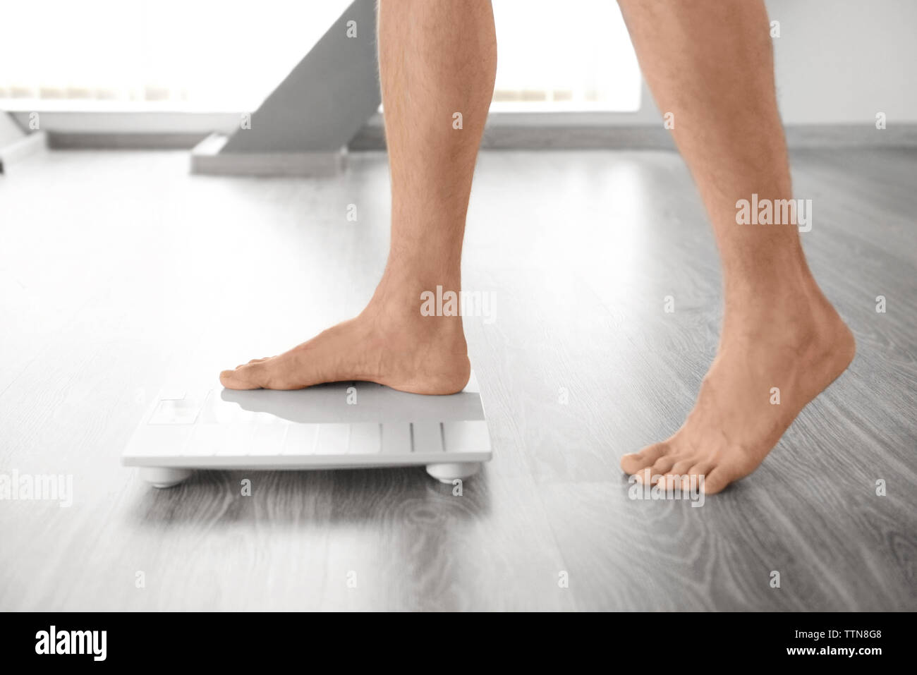 Man standing on weight scale Stock Photo - Alamy