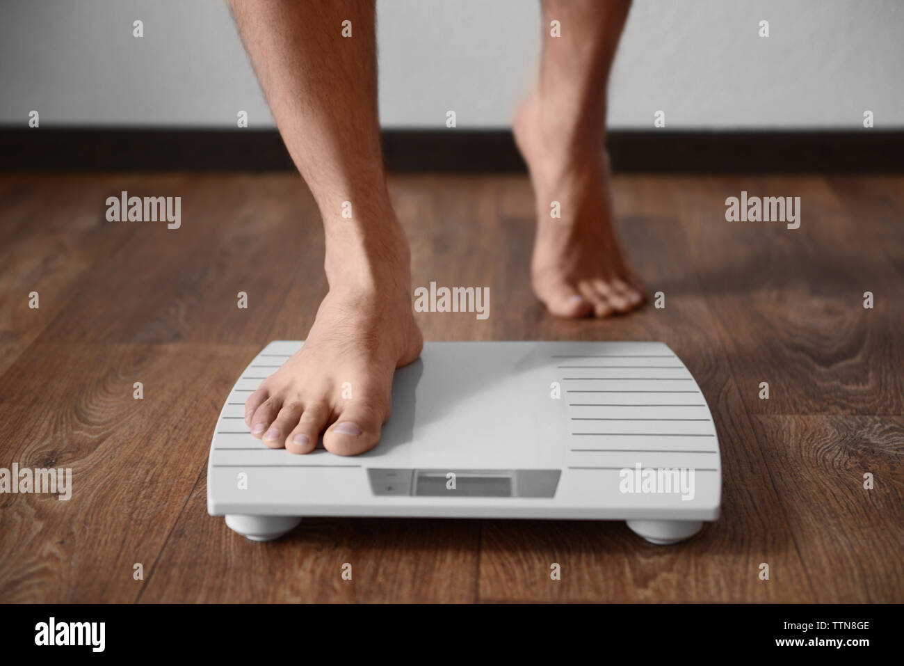 Man standing on weight scale Stock Photo - Alamy