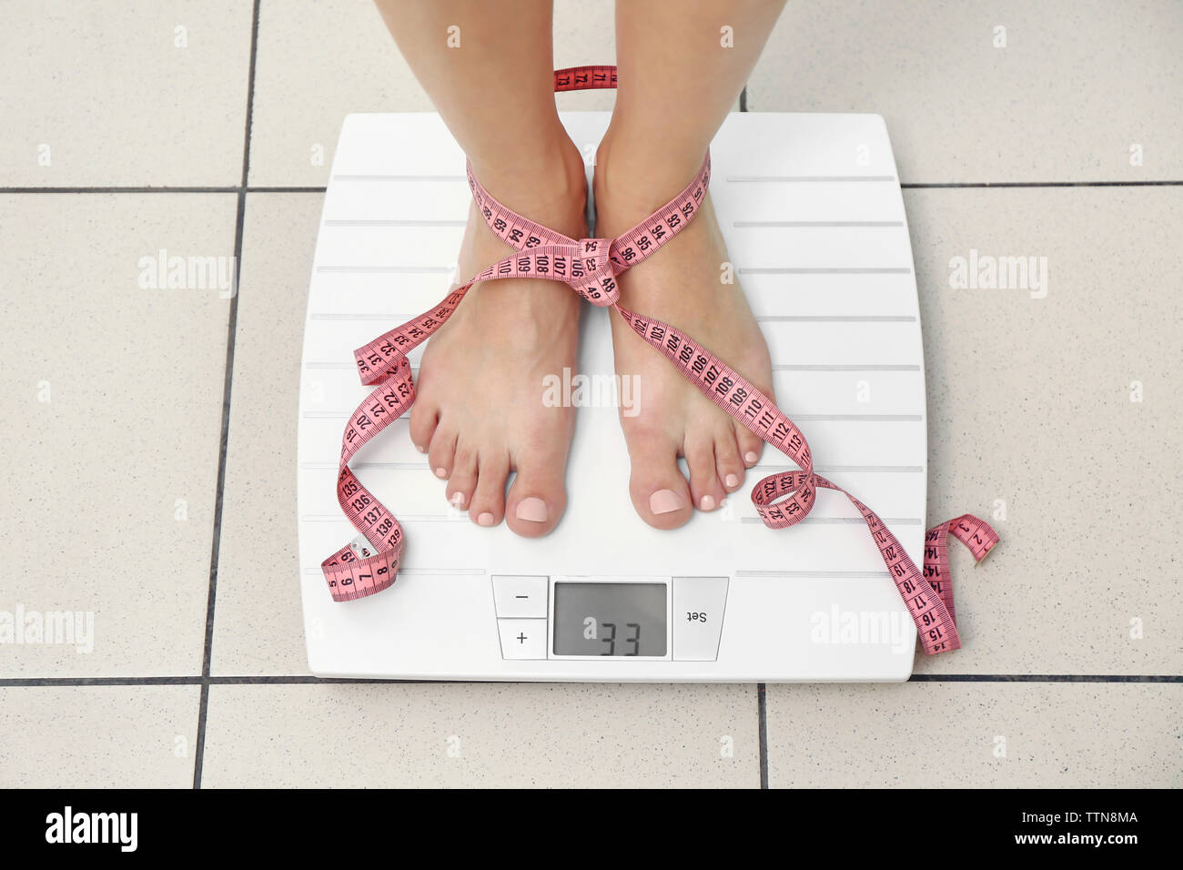 Female legs standing on floor scales with centimeter Stock Photo - Alamy