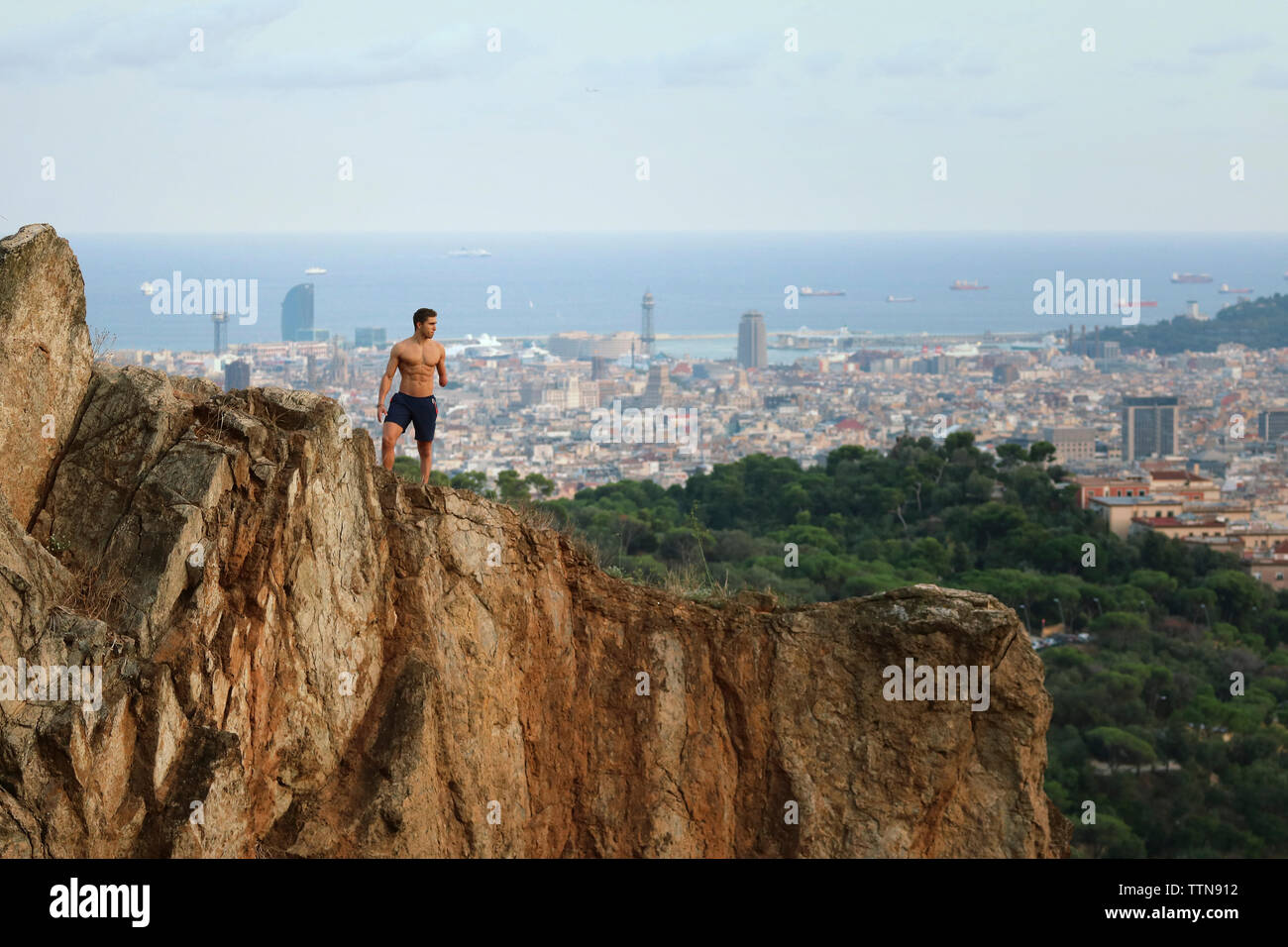 Physically challenged shirtless man standing on cliff against cityscape ...