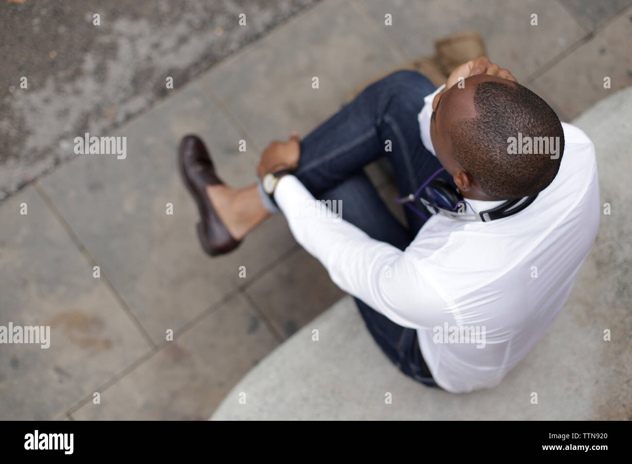 High angle view of man sitting on seat by footpath Stock Photo - Alamy