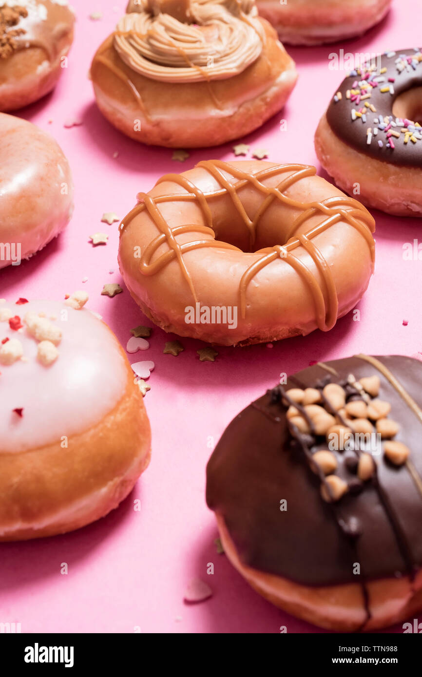 High angle view of various donuts with confetti arranged on pink ...