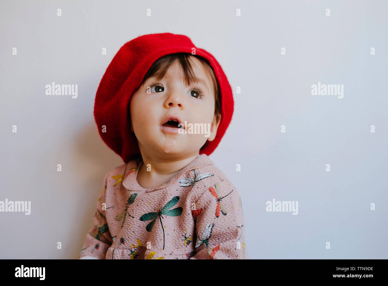 Cute baby girl drooling while looking up against wall at home Stock ...
