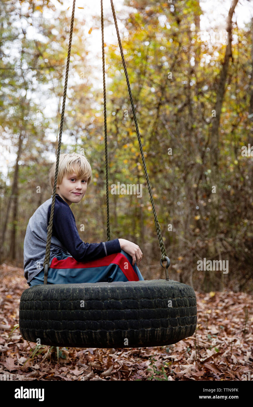 Portrait of boy sitting on tire swing Stock Photo - Alamy