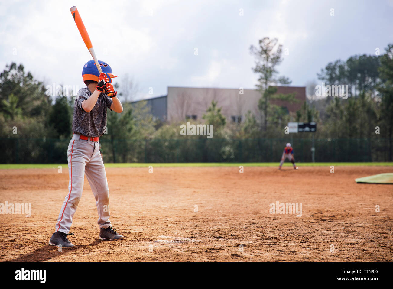 Side view of boy swinging baseball bat on field Stock Photo - Alamy