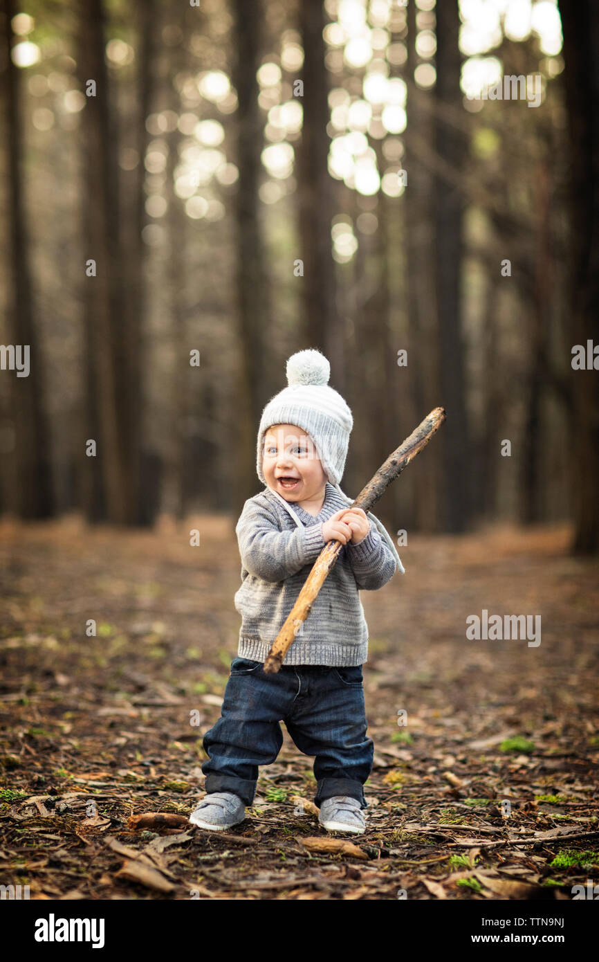 Playful baby boy holding stick while standing on field Stock Photo - Alamy