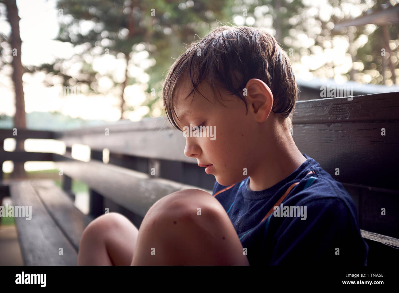 Thoughtful boy sitting on bench at park Stock Photo - Alamy