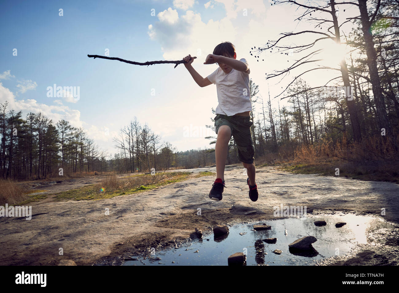 Boy jumping over puddle on Arabia Mountain against cloudy sky Stock ...
