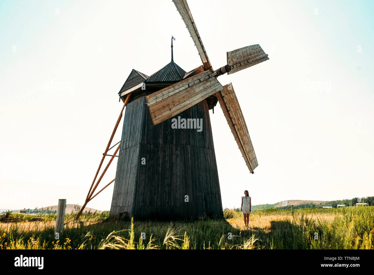 Woman standing by traditional windmill on field against clear sky Stock ...