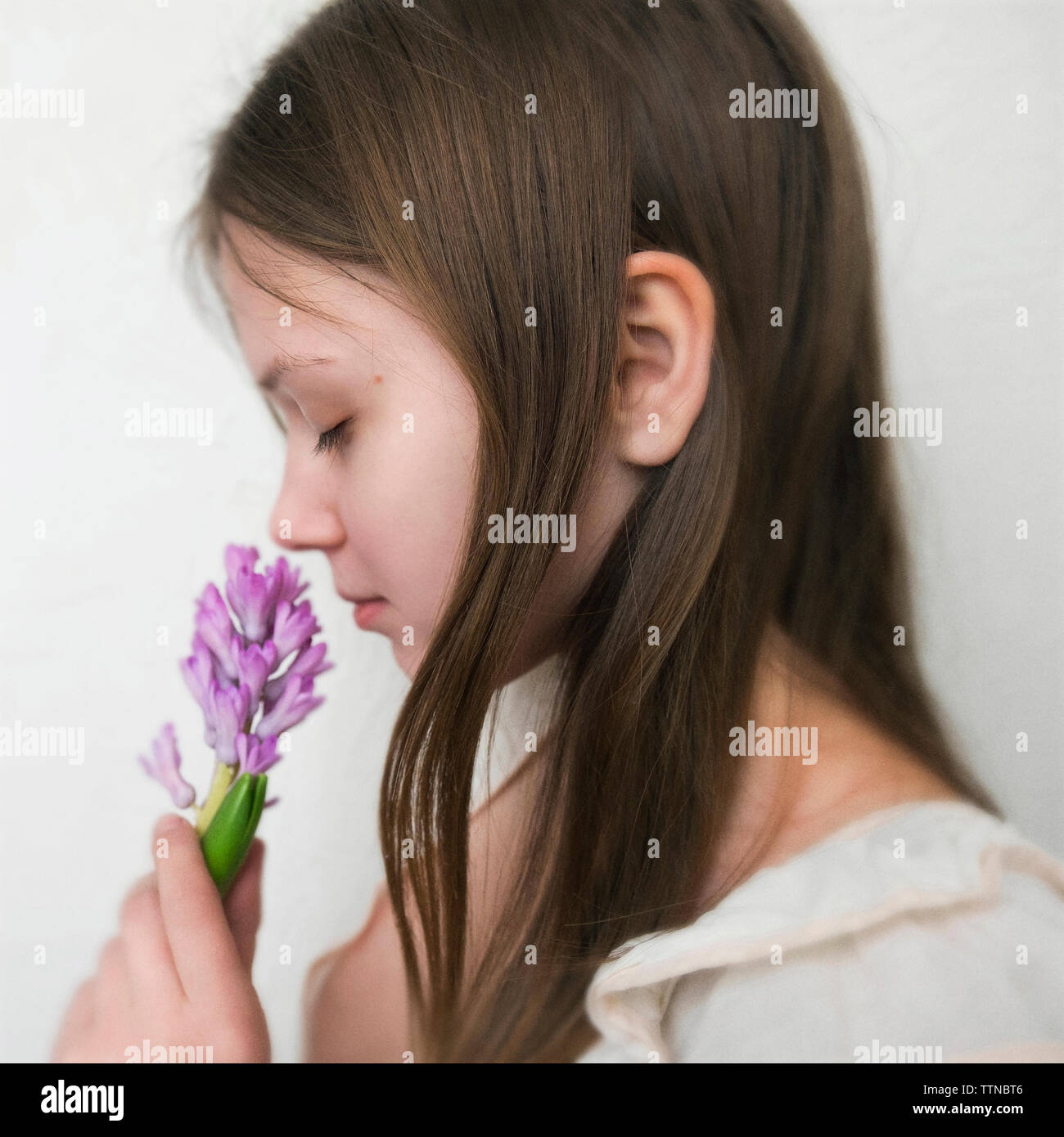 Side view of woman with eyes closed smelling flowers while standing ...