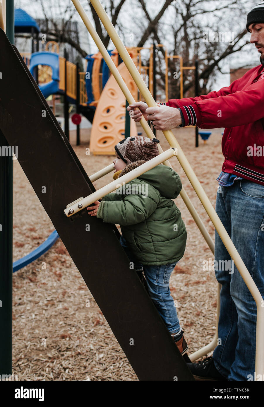 Father assisting son in climbing slide at playground Stock Photo - Alamy