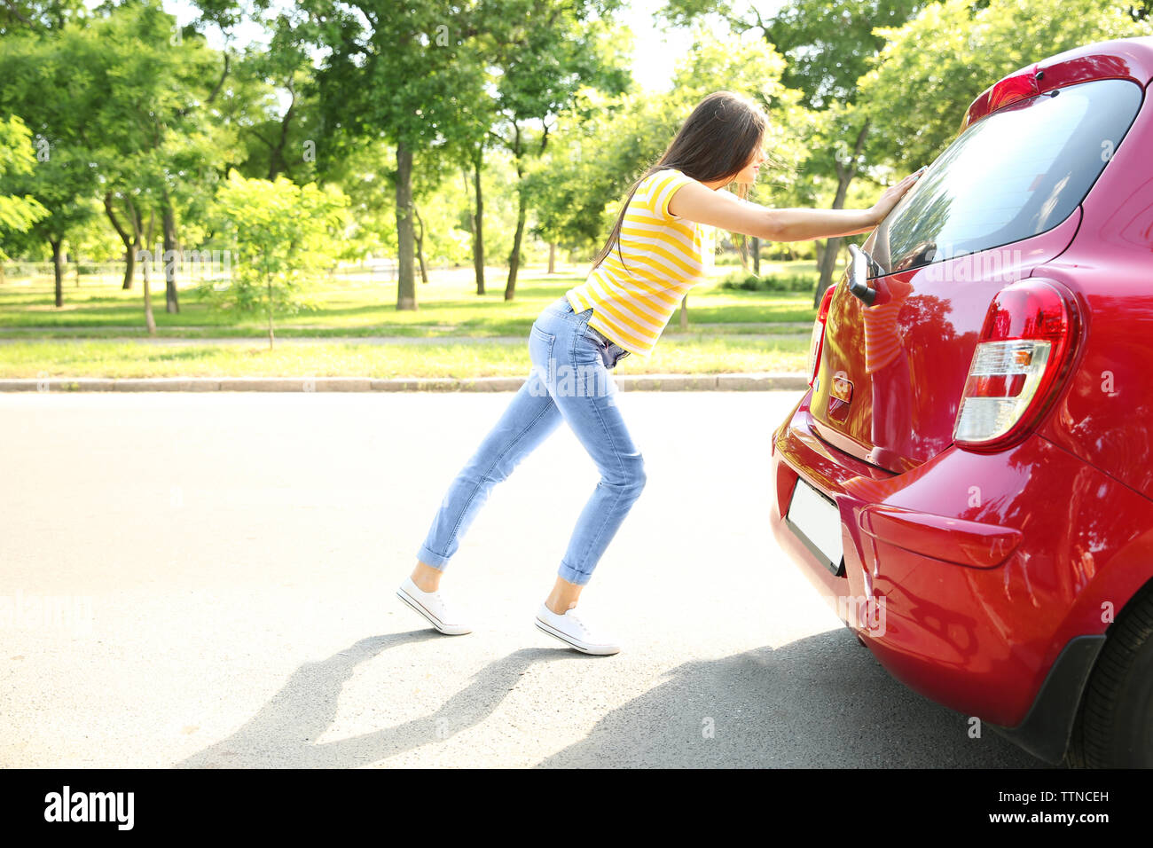 Woman pushing red car Stock Photo - Alamy