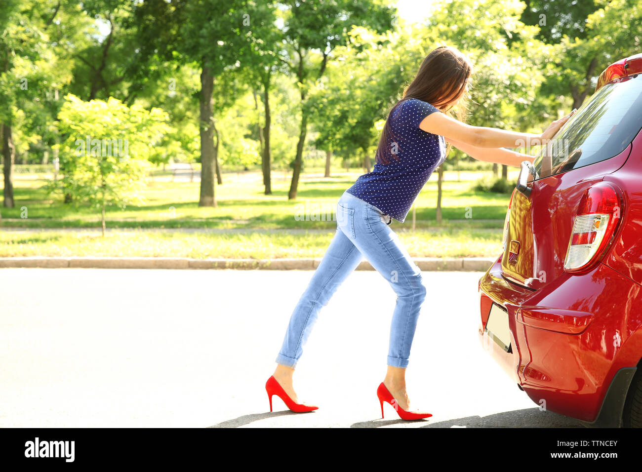 Woman pushing red car Stock Photo - Alamy